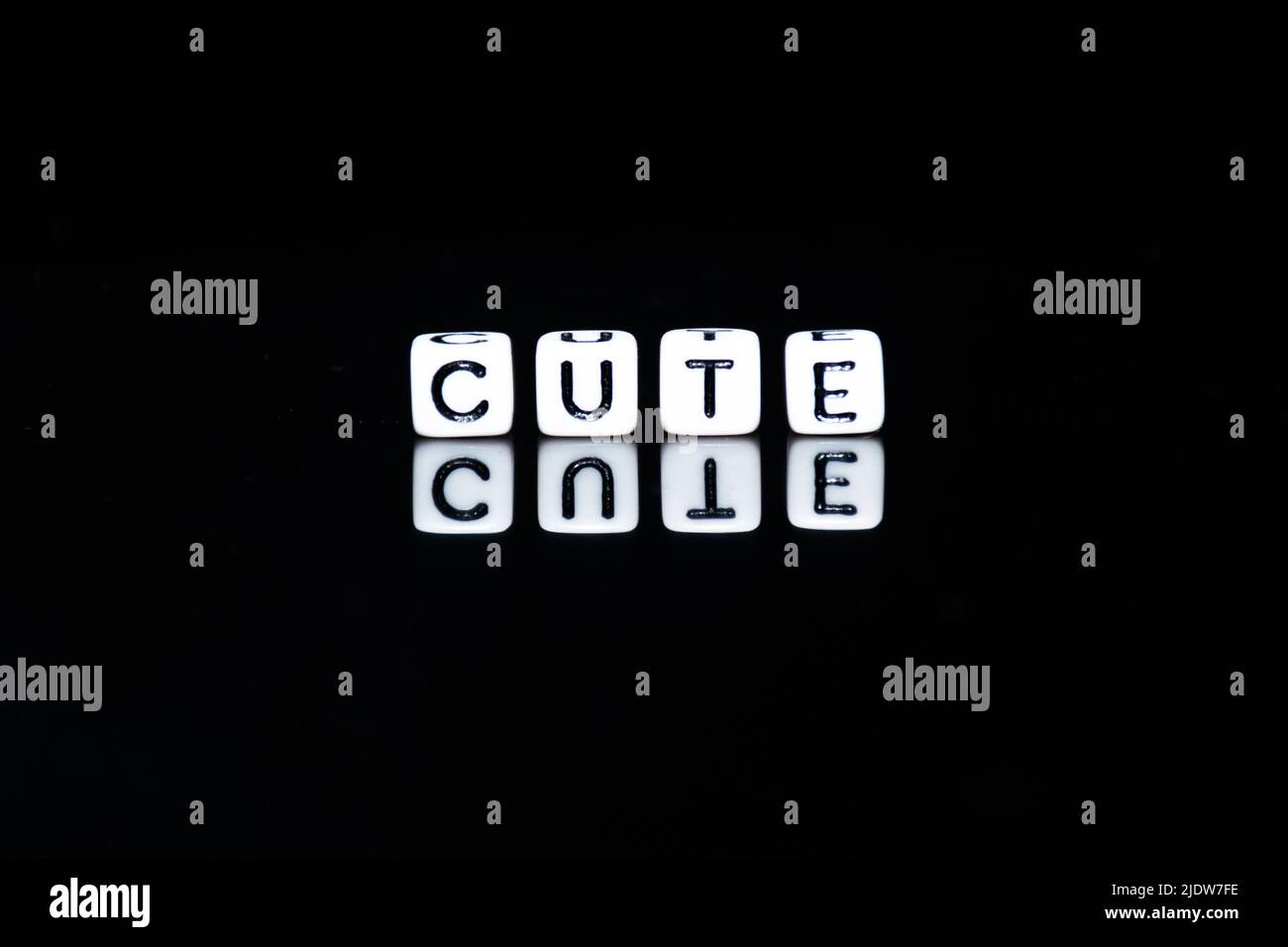 The word of "CUTE" making from little acrylic cubes in black background ...