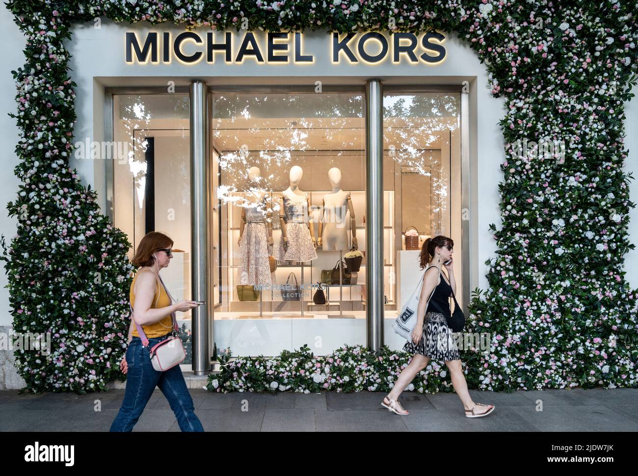 Pedestrians walk past the American clothing fashion store brand Michael ...