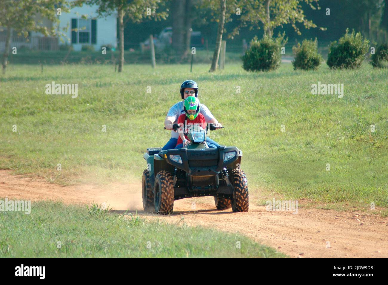 Father and Son on 4 wheeler on dirt road during learning session for ...