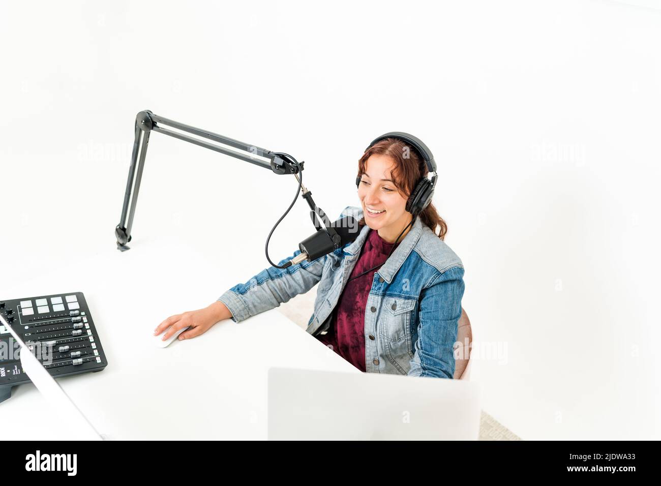 Woman smiling in front of microphone wearing headphones with mixing ...