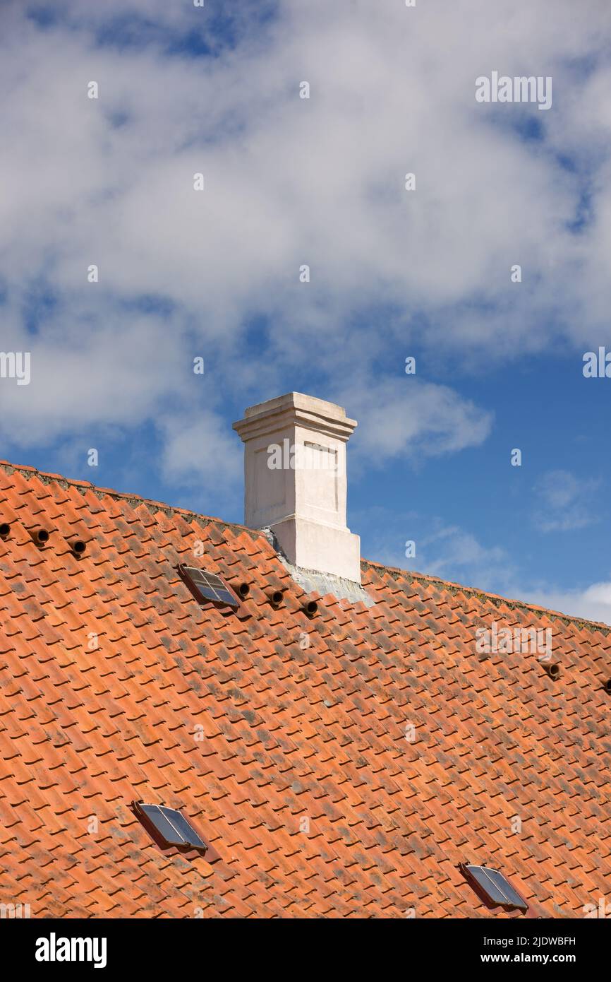 Chimney designed on slate roof of house building outside against blue ...