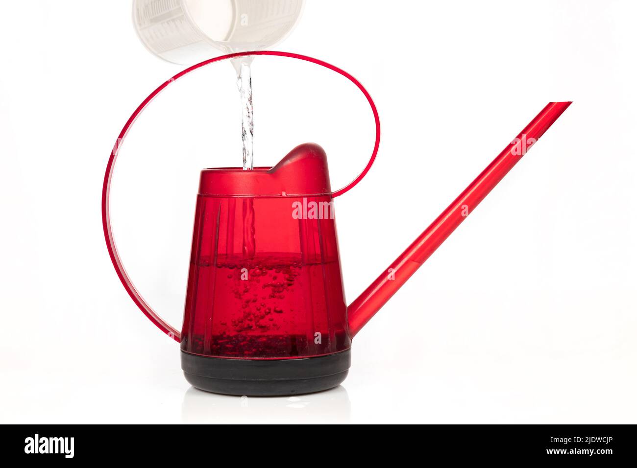 Red Plastic Watering Can Isolated On White Background Being Filled With Water From An Overhead