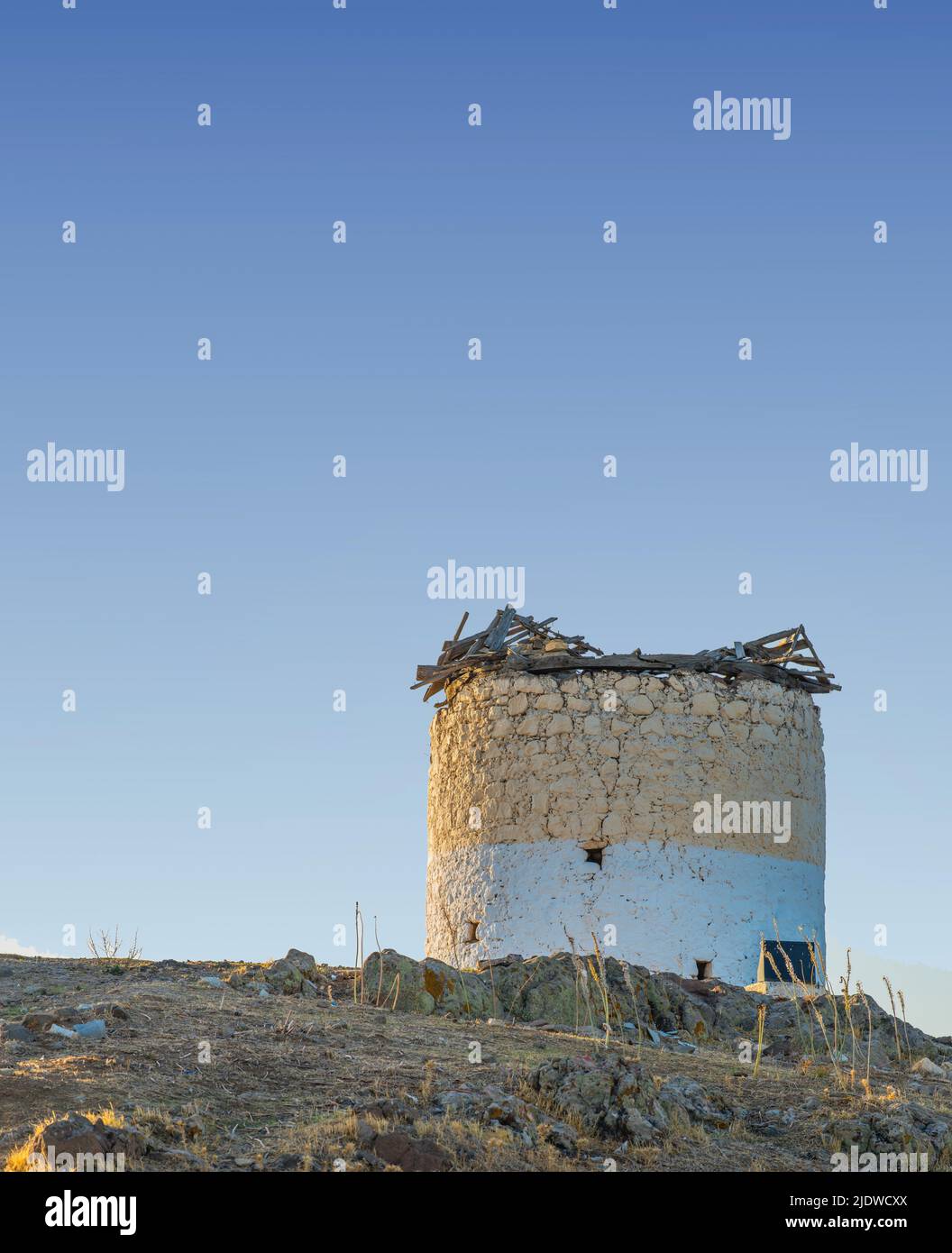 Old windmill in ruin on a hill with a scenic background of the blue sky ...