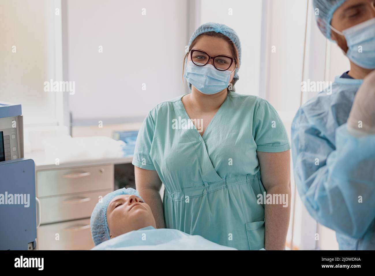 Portrait of nurse assisting doctors during surgery in operation room of ...