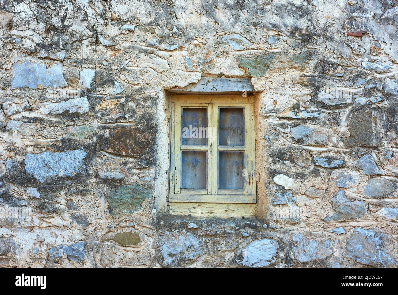 Wooden window on an old rough stone wall farmhouse or ancient house ...