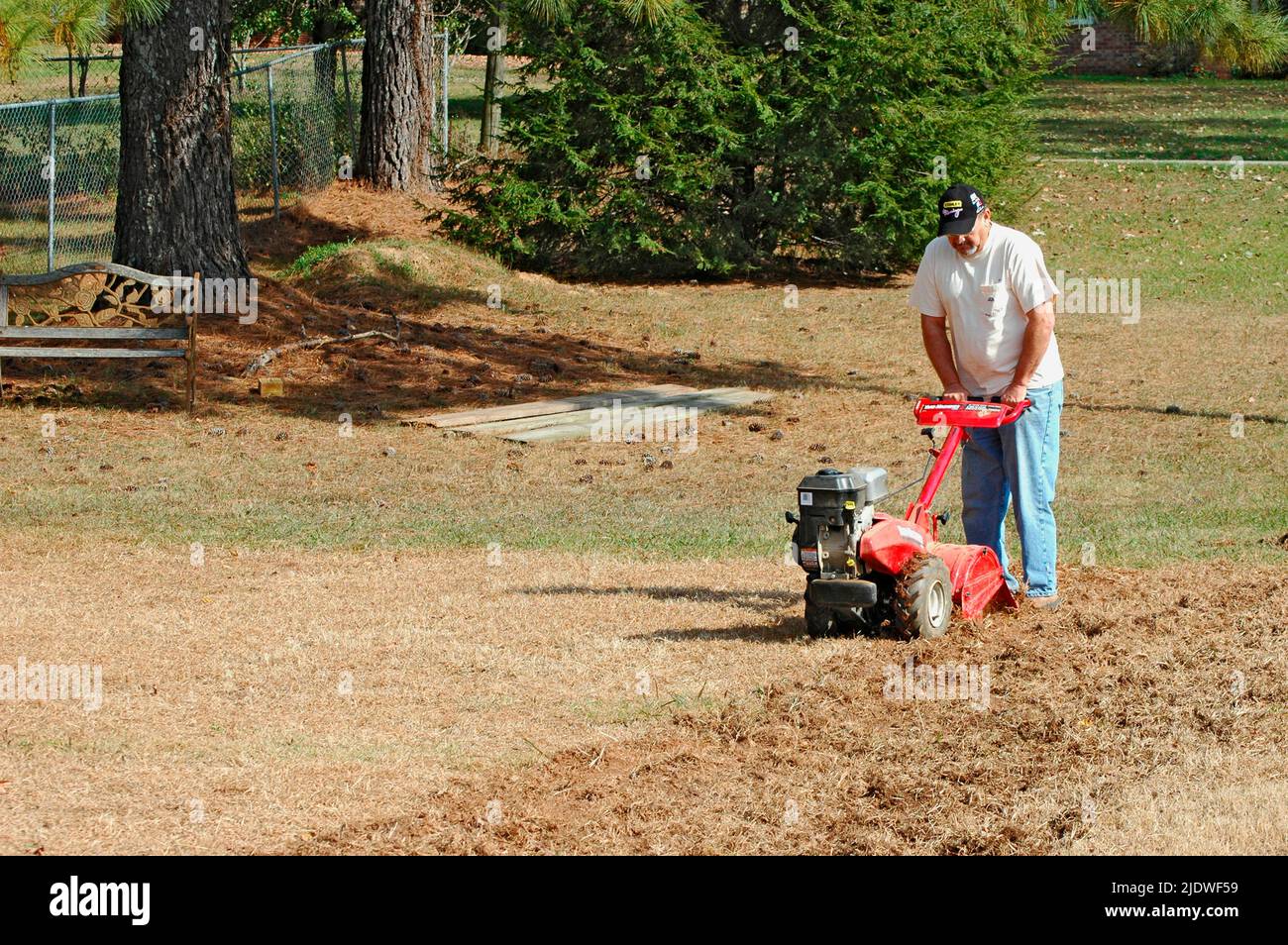 Men roto tilling a public lawn to put in garden with tillers, front and ...