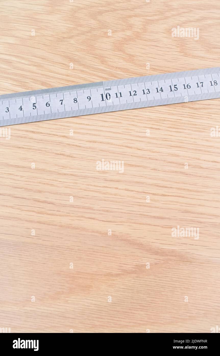 metal ruler on a bright wooden desk, view from above with space for ...