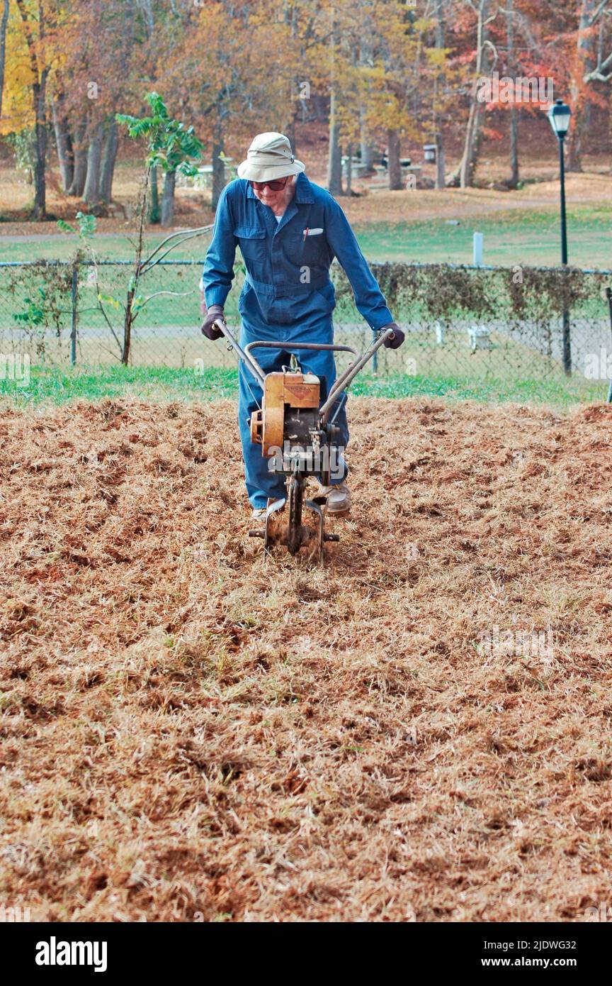 Men roto tilling a public lawn to put in garden with tillers, front and ...
