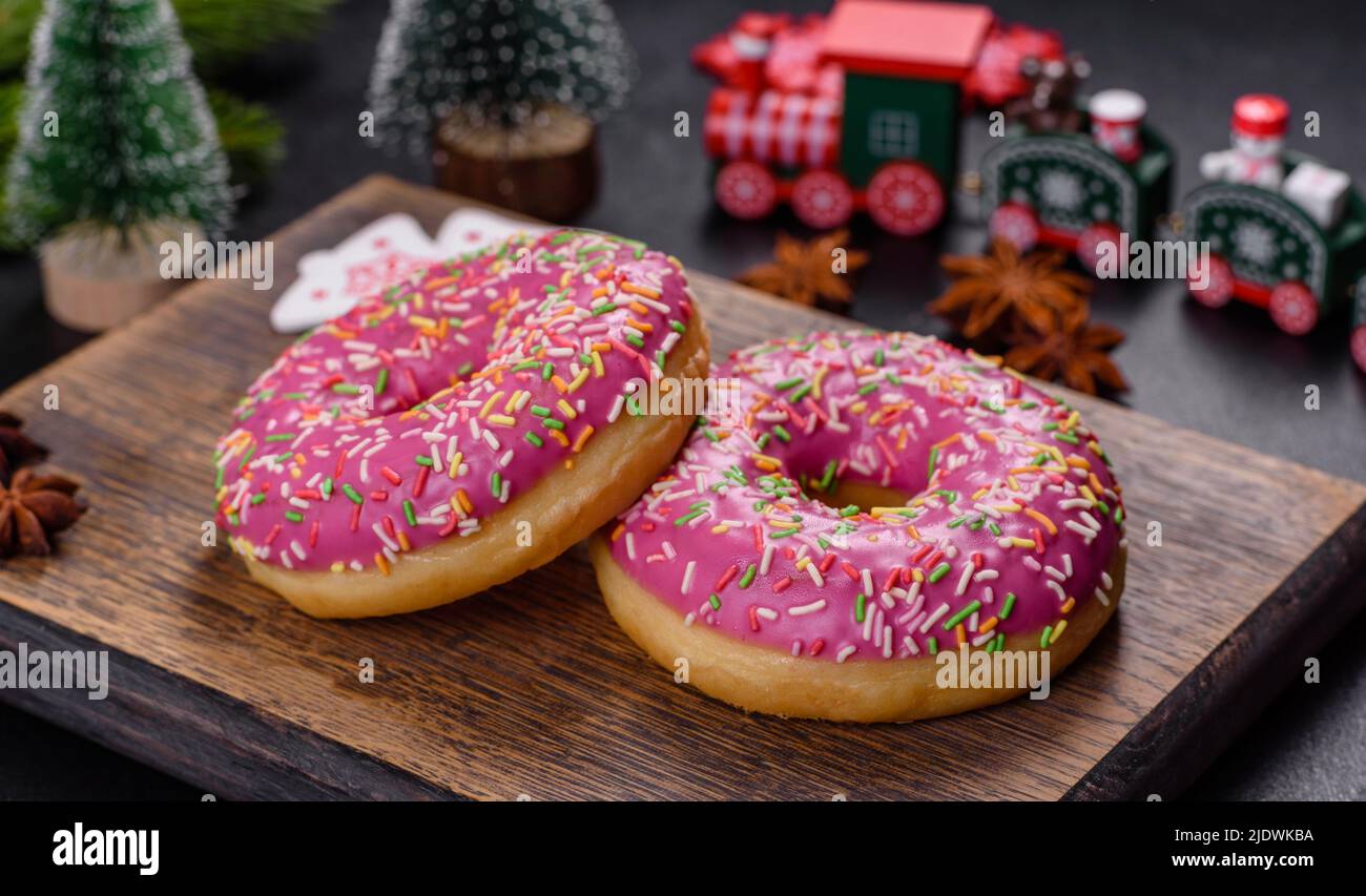 A beautiful doughnut with pink glaze and colored sprinkle on a dark ...