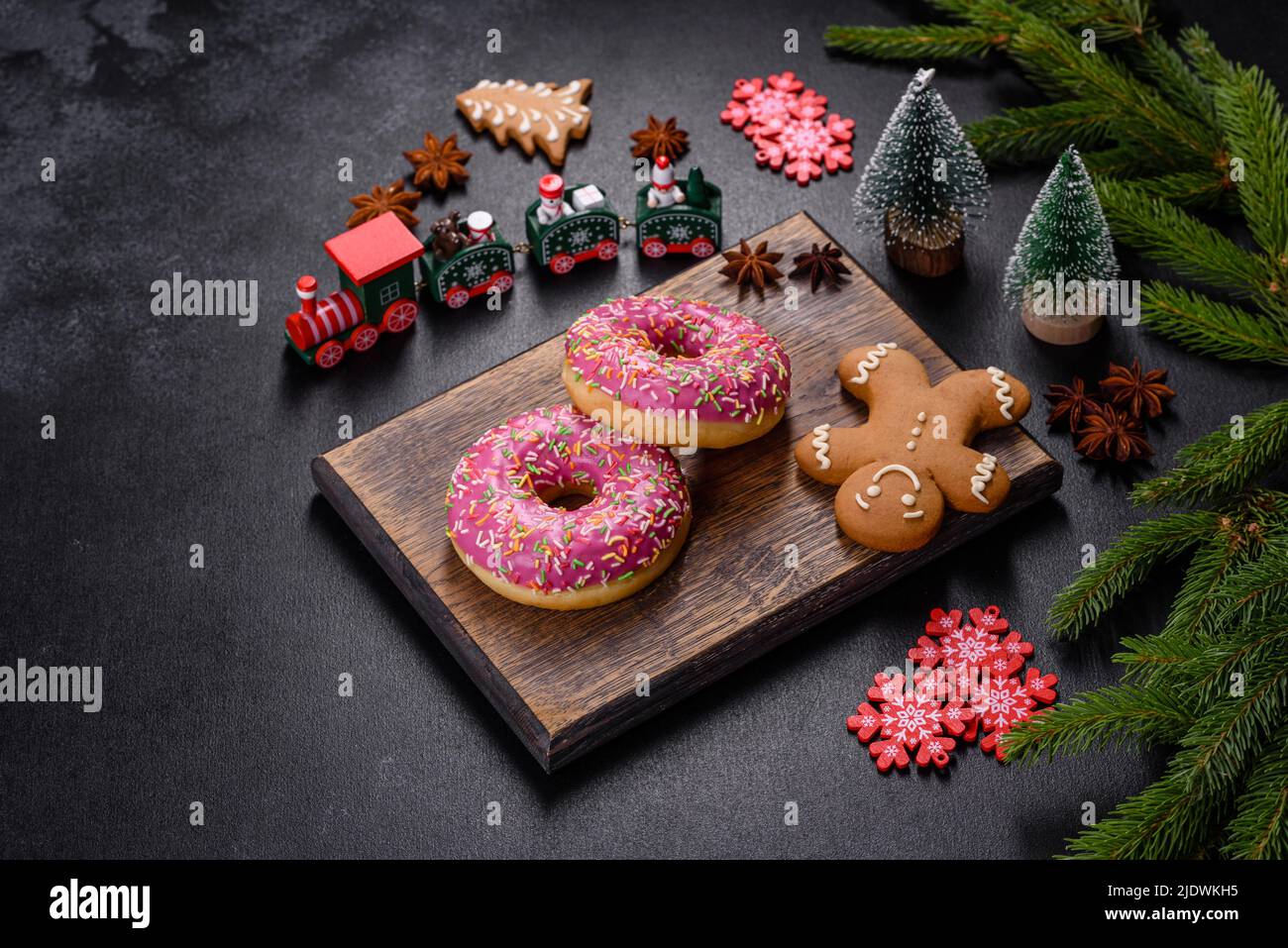 A beautiful doughnut with pink glaze and colored sprinkle on a dark ...