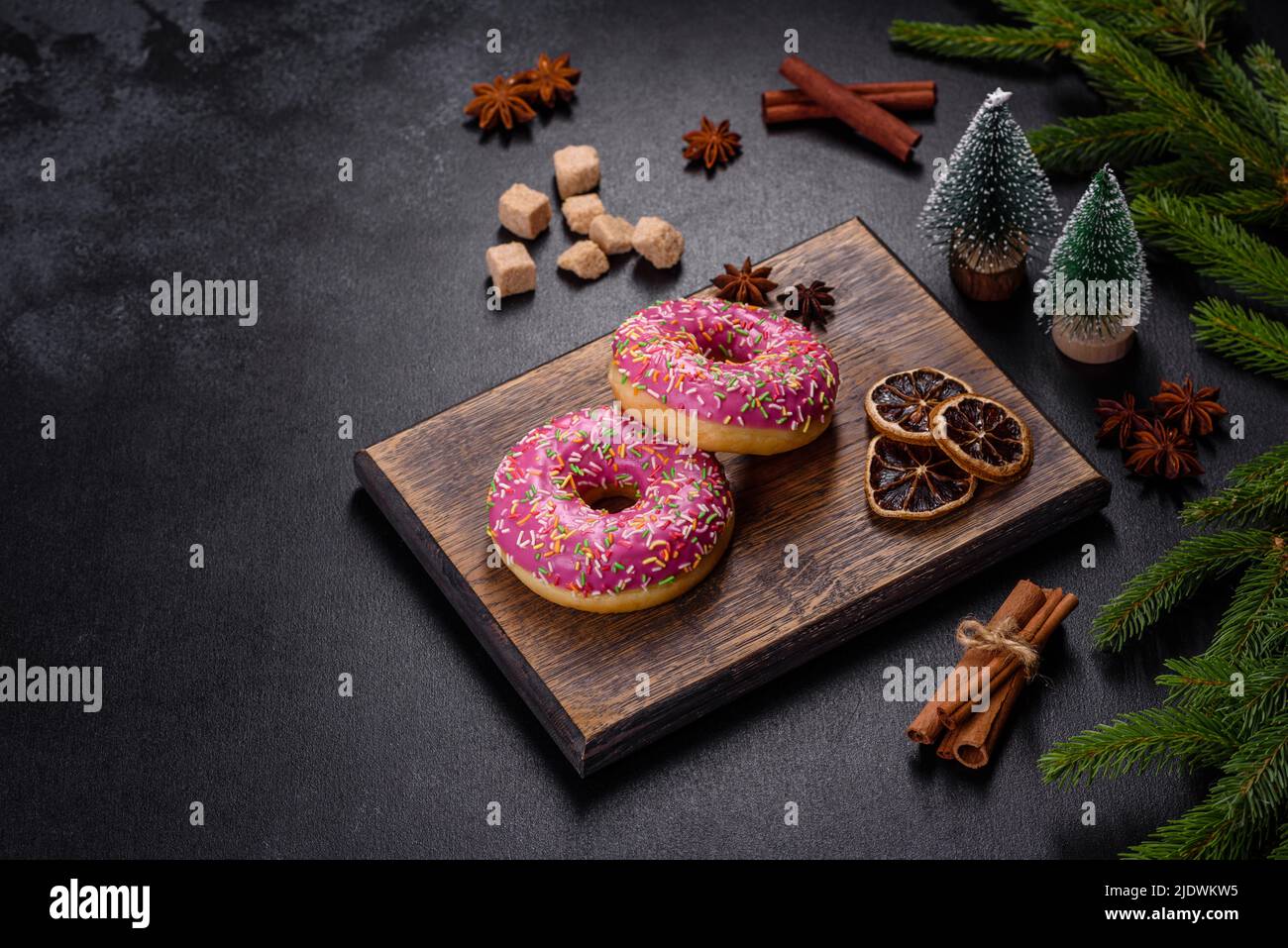 A beautiful doughnut with pink glaze and colored sprinkle on a dark ...