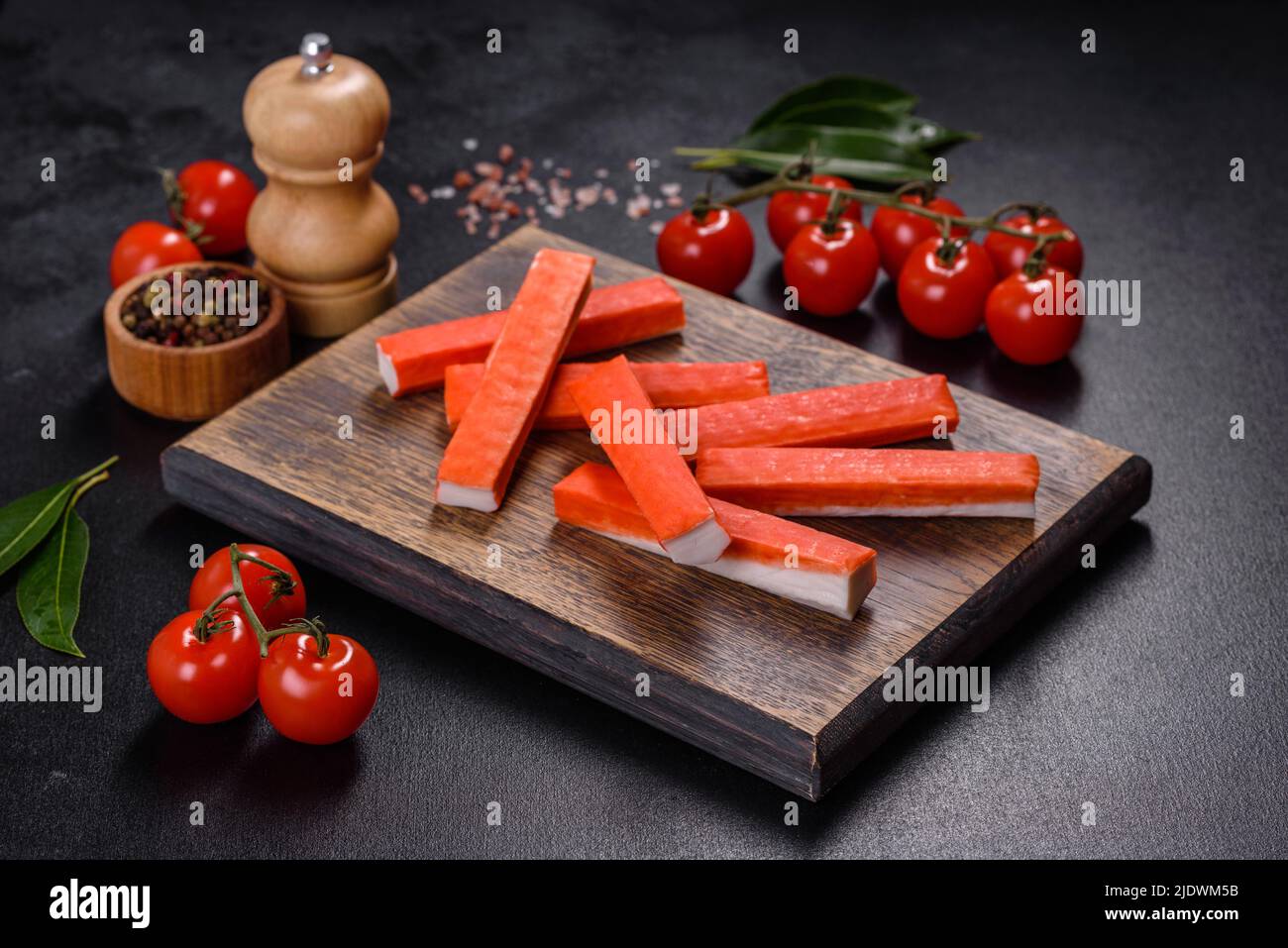 Sliced crab sticks on a cutting Board with a knife. On black rustic ...