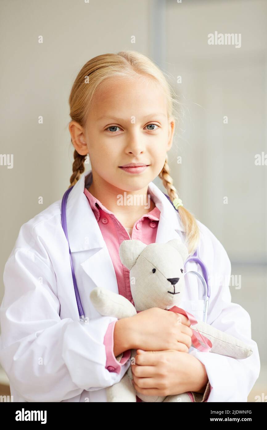 Content cute girl in doctor dress as lab coat and stethoscope embracing ...
