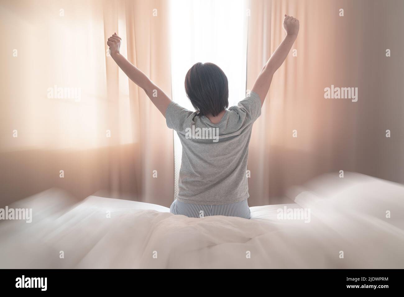 Woman stretching in bed after wake up, soft tone with motion blur ...