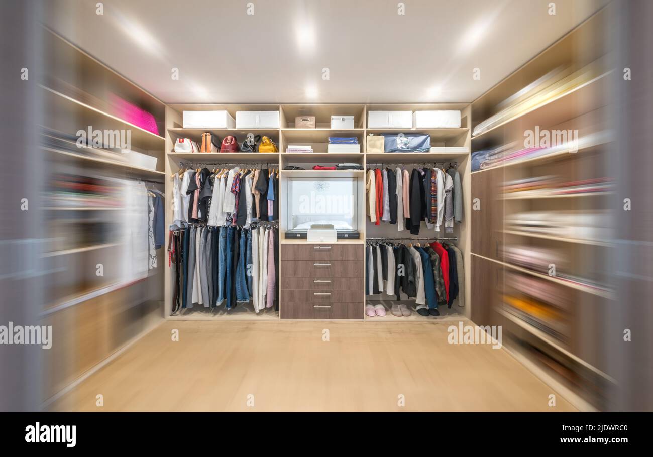 Big wardrobe with different clothes for dressing room with motion blur ...