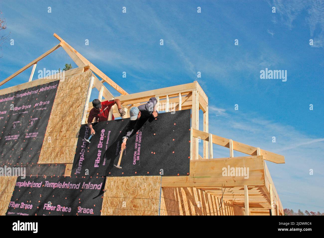 Installing insulation on new home construction of wood and fiber by ...