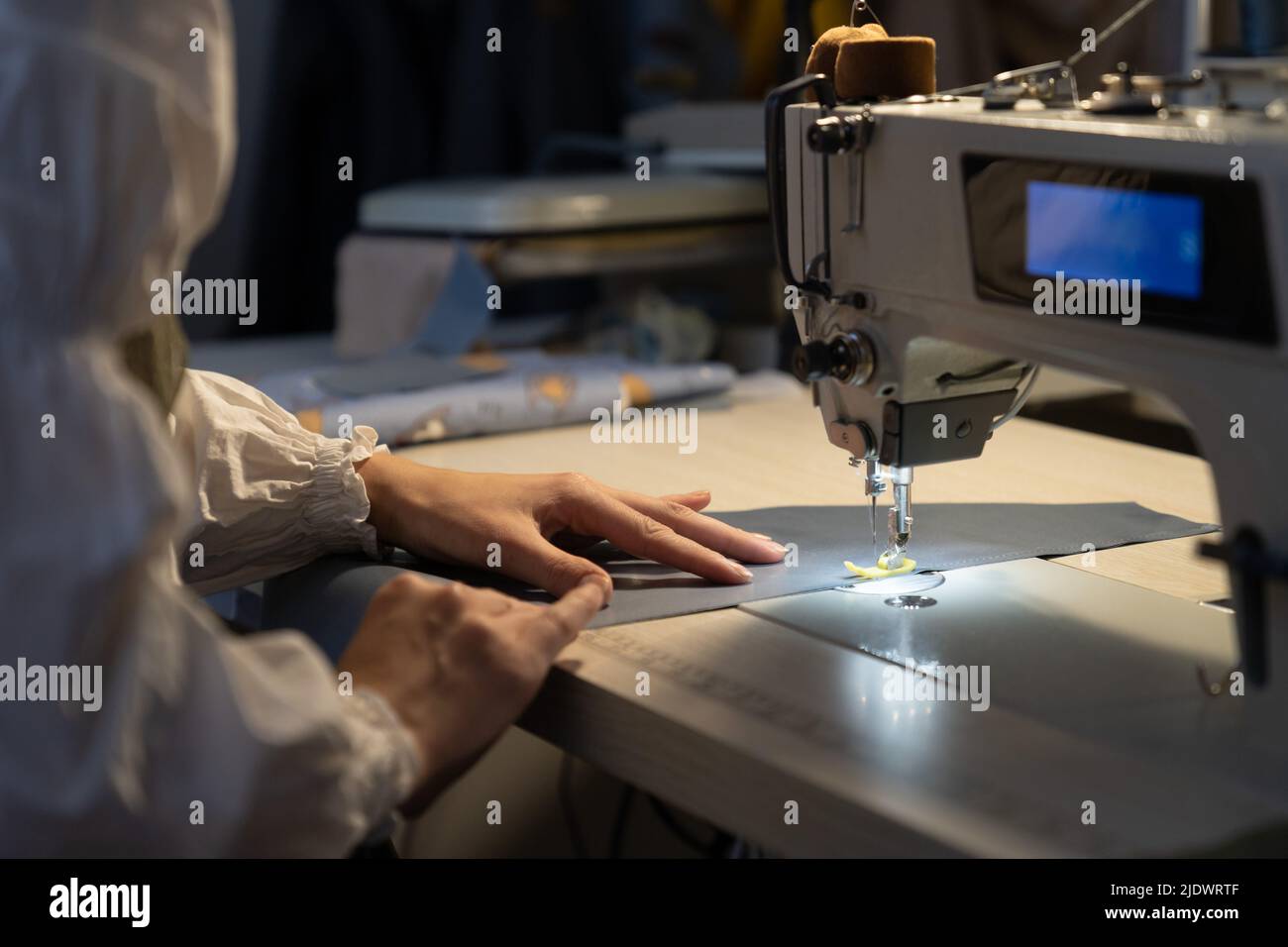 Closeup of female tailor work on sewing machine stitch fabric patterns ...