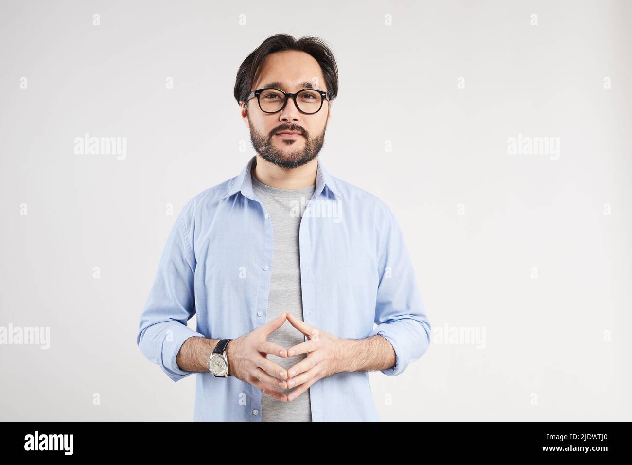 Portrait of thoughtful young Asian man in shirt and glasses standing ...