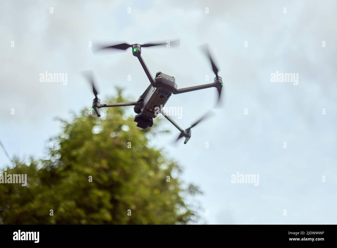 Drone flying overhead in cloudy blue sky Stock Photo - Alamy