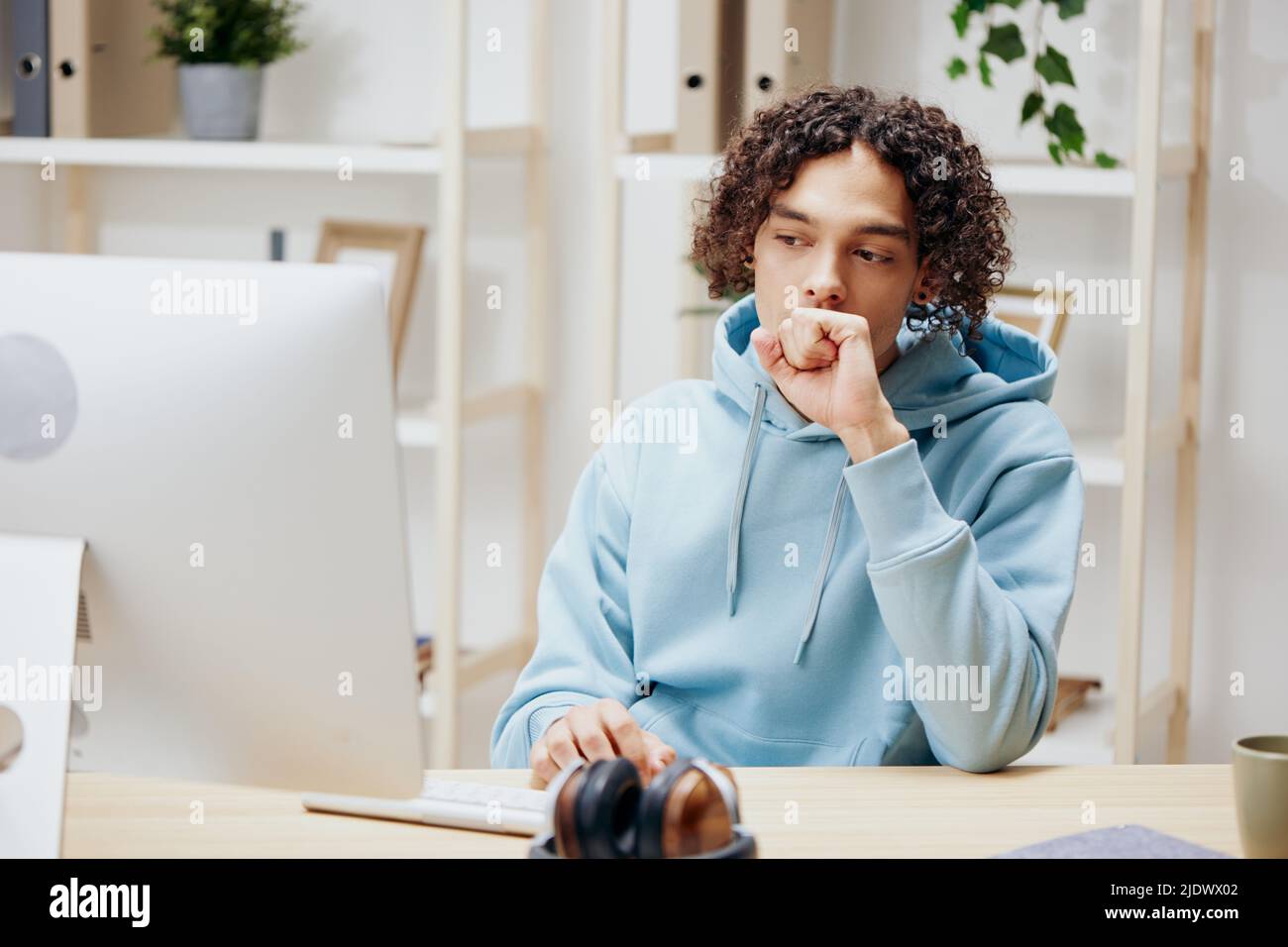A young man sitting at a table in front of a computer freelance ...