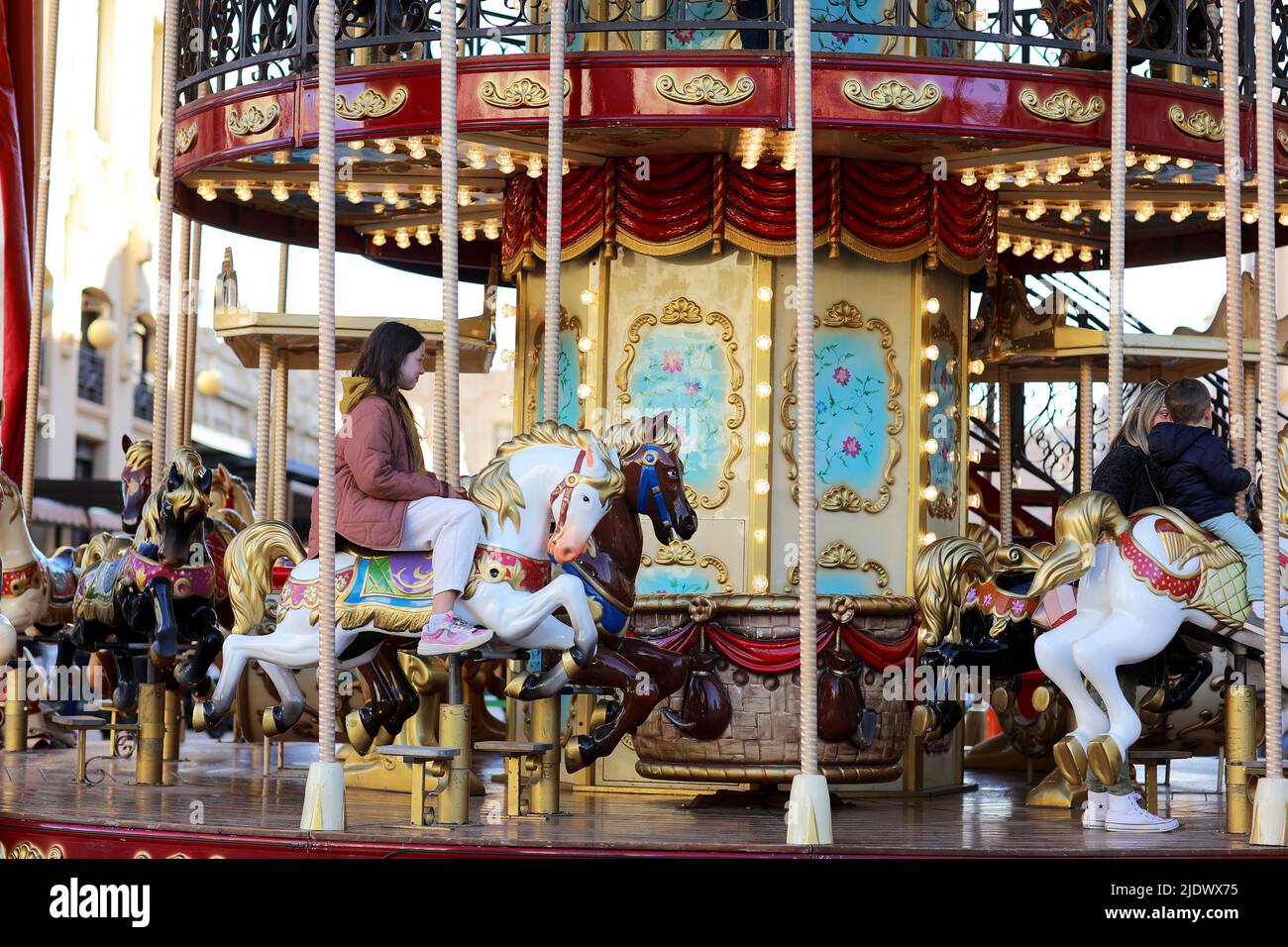 a little girl riding on animals on roundabout carousel in amusement ...