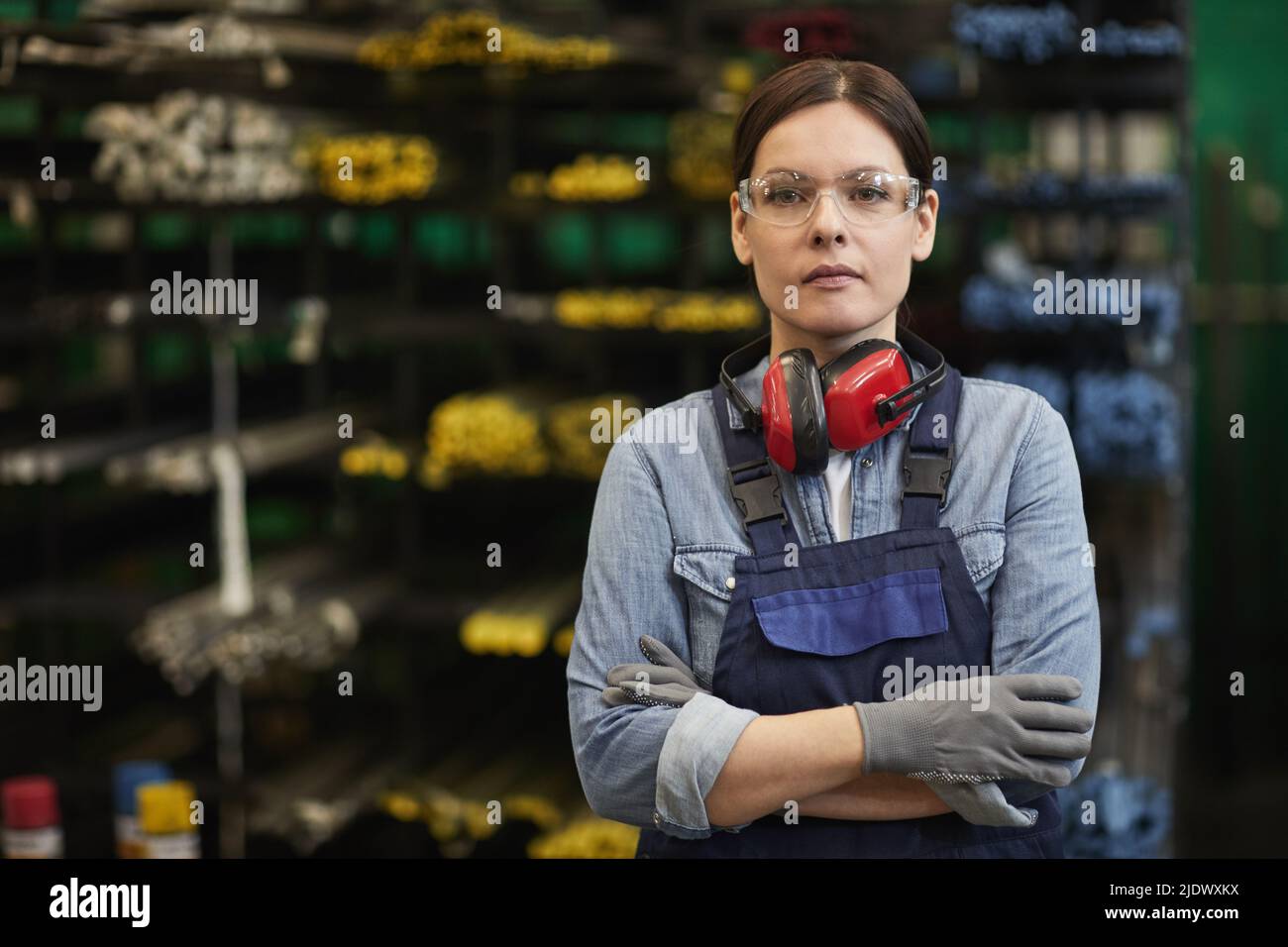 Serious confident professional female worker of factory wearing gloves ...