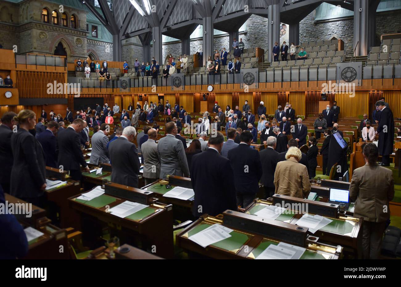 Members of Parliament in the House of Commons chamber rise for a moment ...