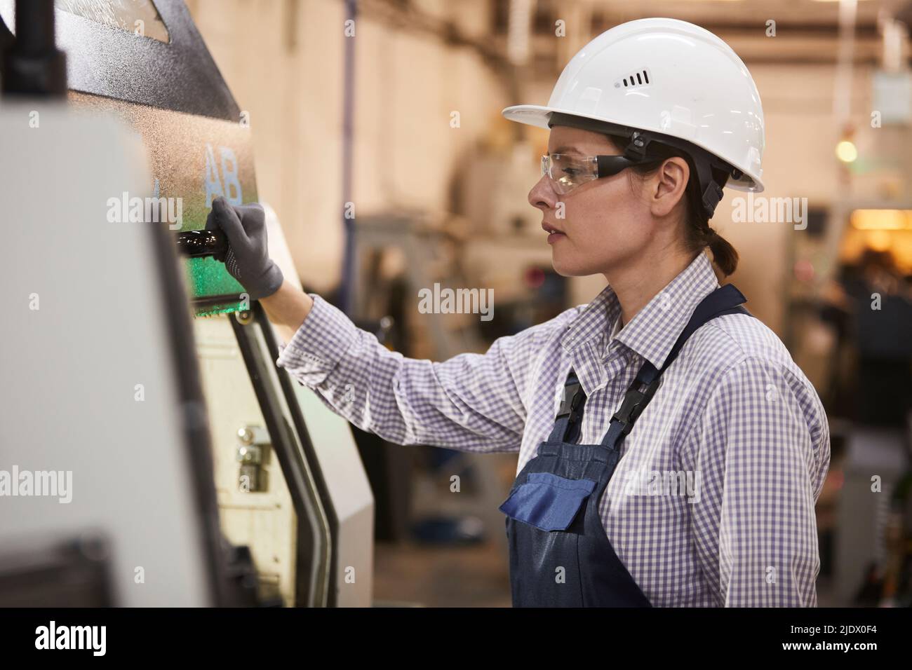Concentrated gritty young woman in hardhat and safety goggles preparing ...