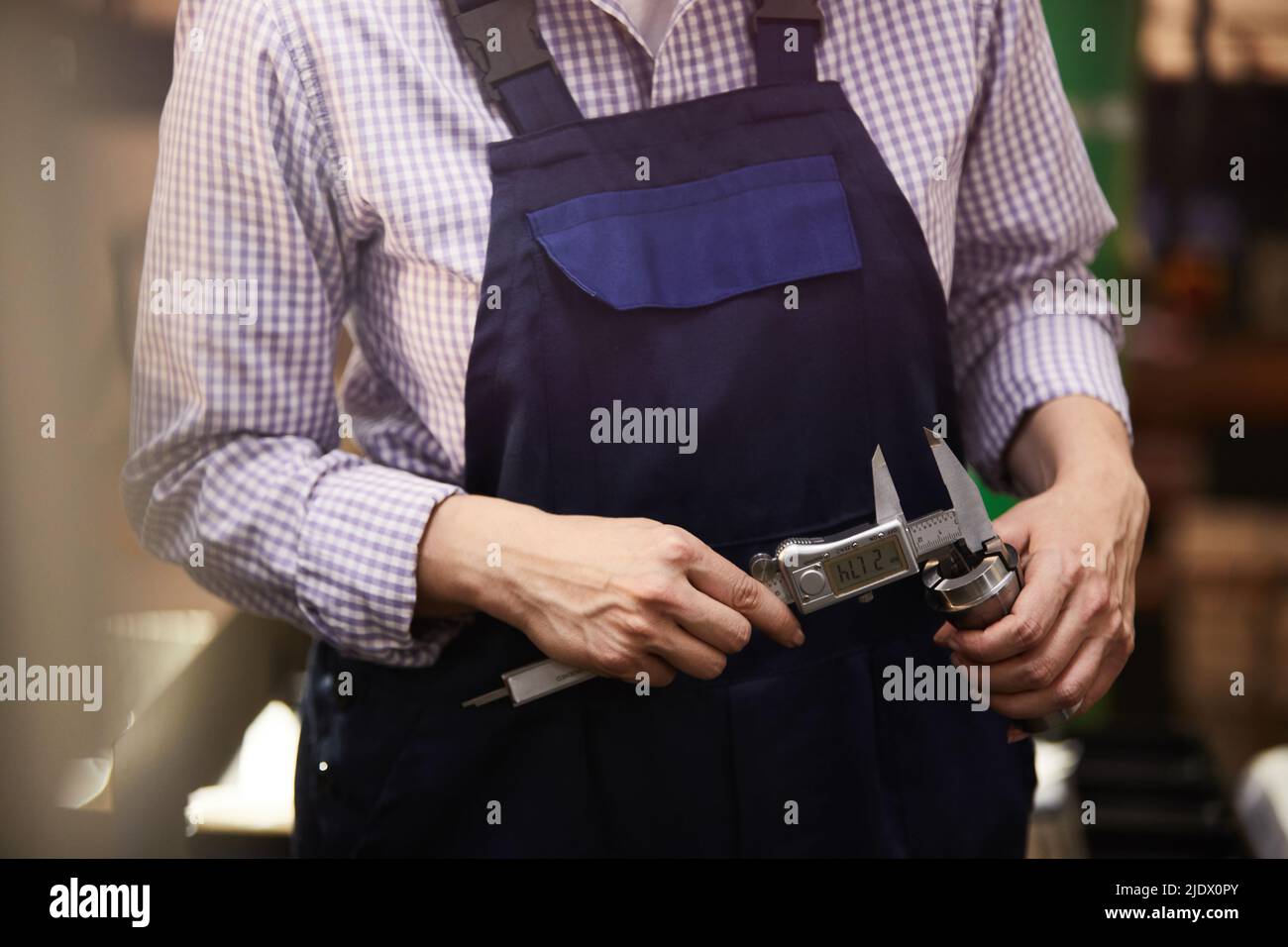 Close-up of unrecognizable factory worker in dark blue overalls ...
