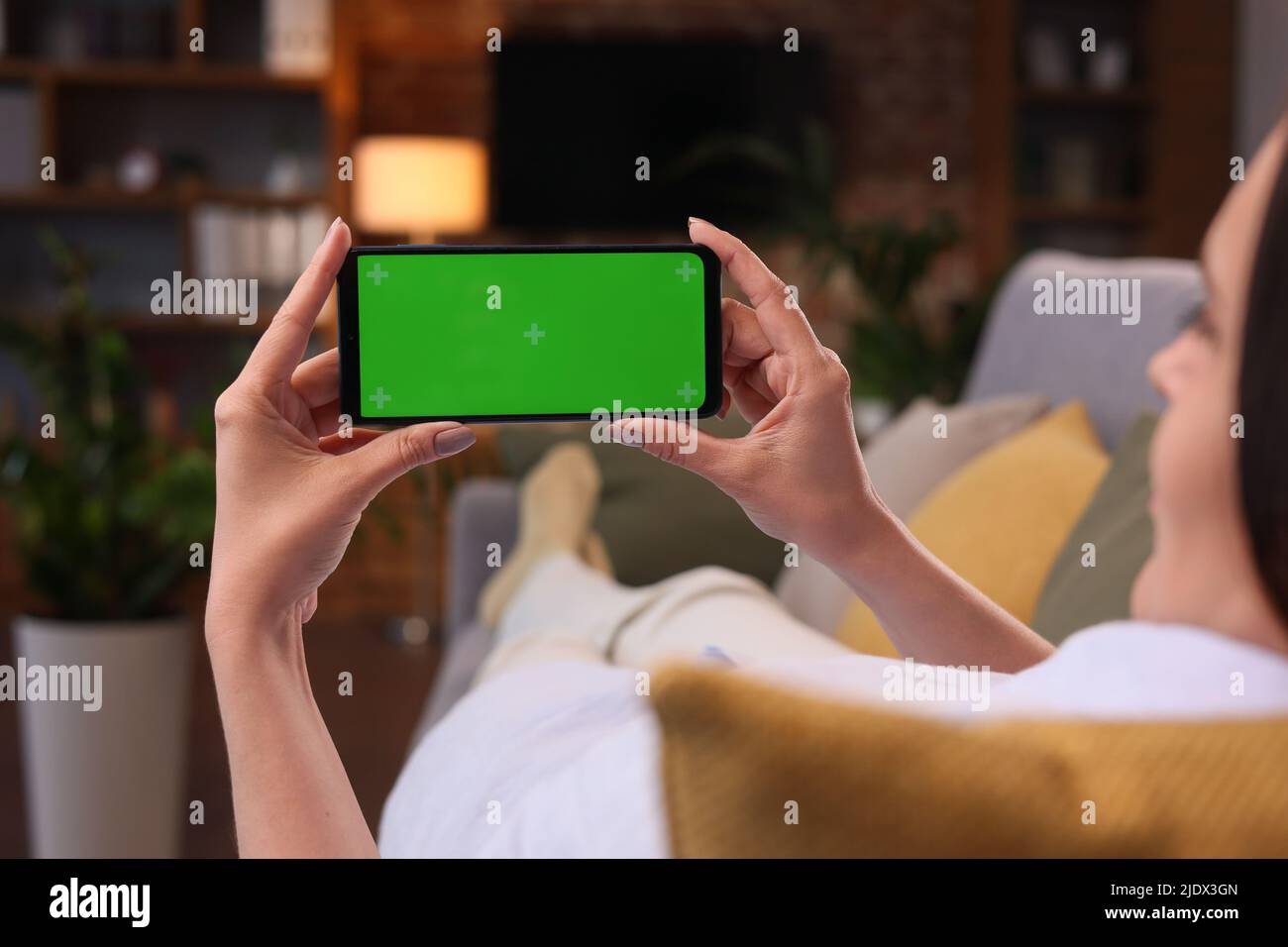 Over shoulder view of young woman holding smartphone with green mock-up ...