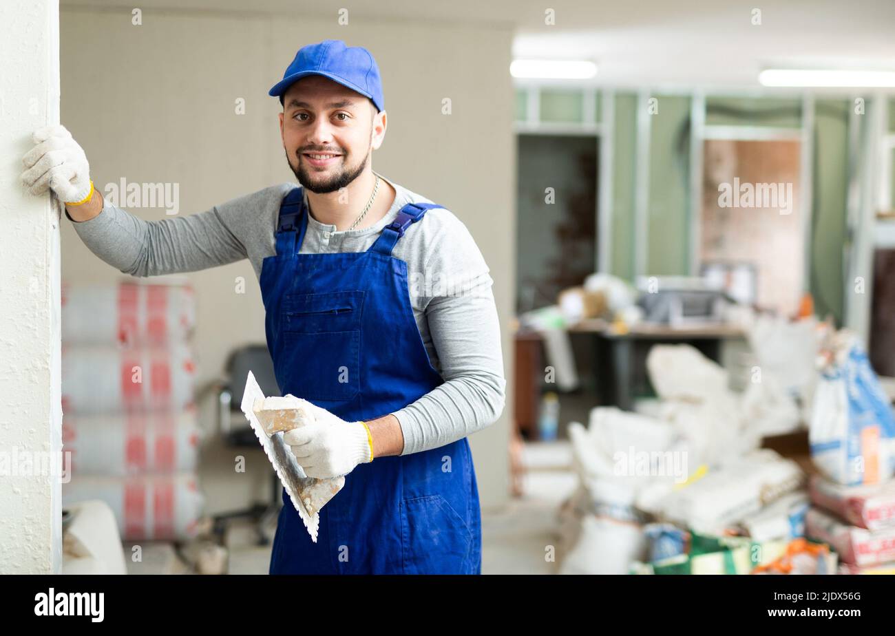 Positive man plasterer posing at renovating object Stock Photo - Alamy