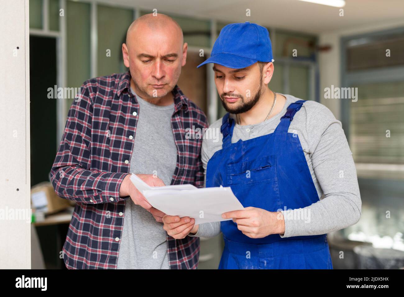 Customer discussing list of tasks with builder in house under ...
