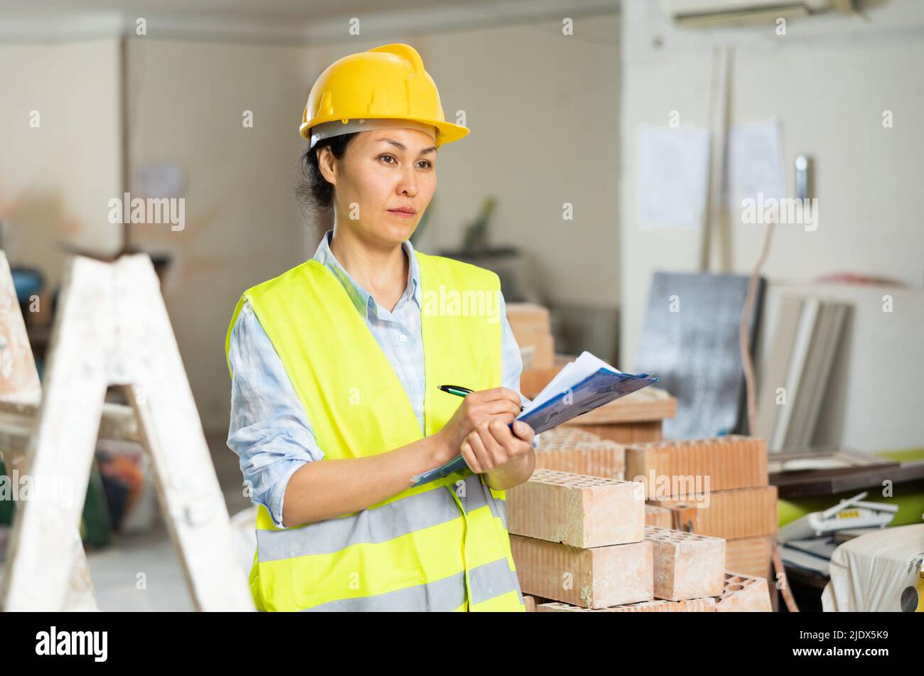 Woman making notes on indoor construction site Stock Photo - Alamy