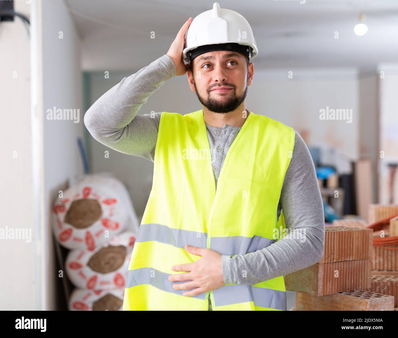 Frustrated worker in yellow vest and hard hat is dissatisfied with the ...
