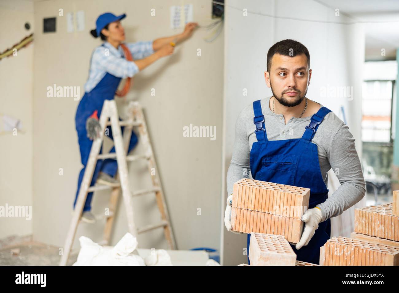 Man builder carrying bricks hi-res stock photography and images - Alamy