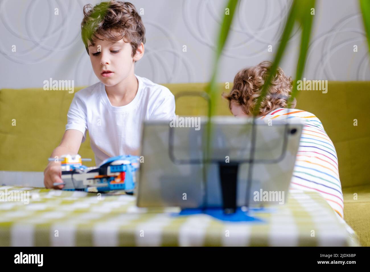 Kid collects robot from plastics details and programmed on tablet ...