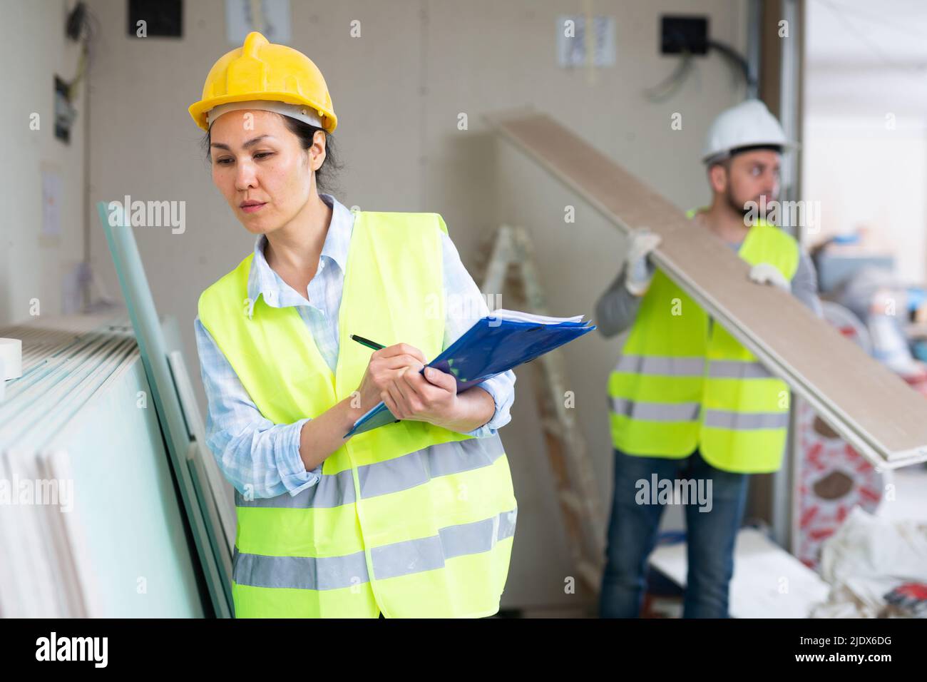 Female building inspector taking inventory of materials at construction ...