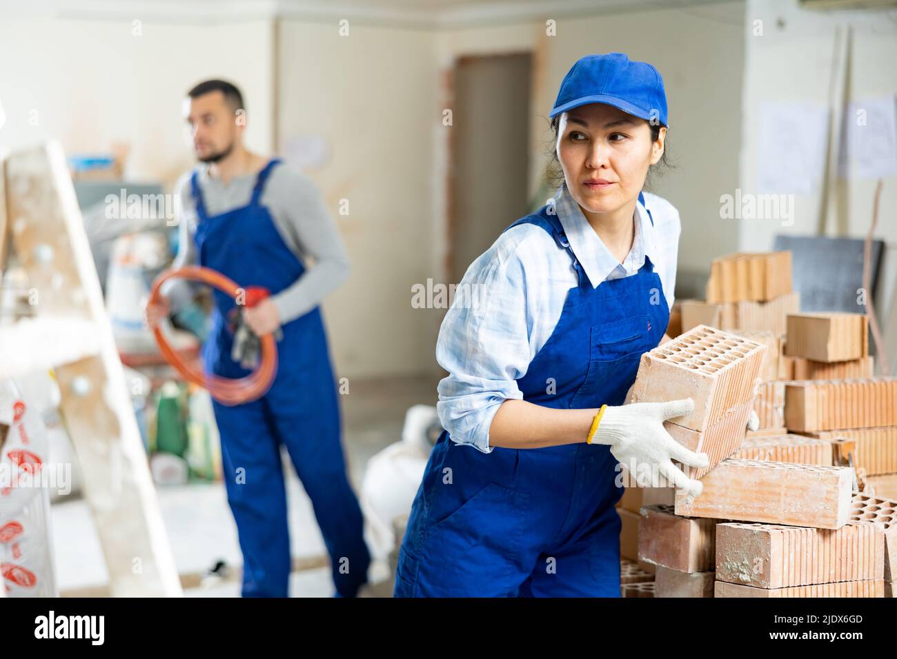 Female builder preparing red bricks in building under reconstruction ...