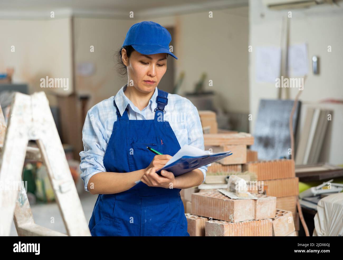 Female builder fills out documentation during repair work Stock Photo ...