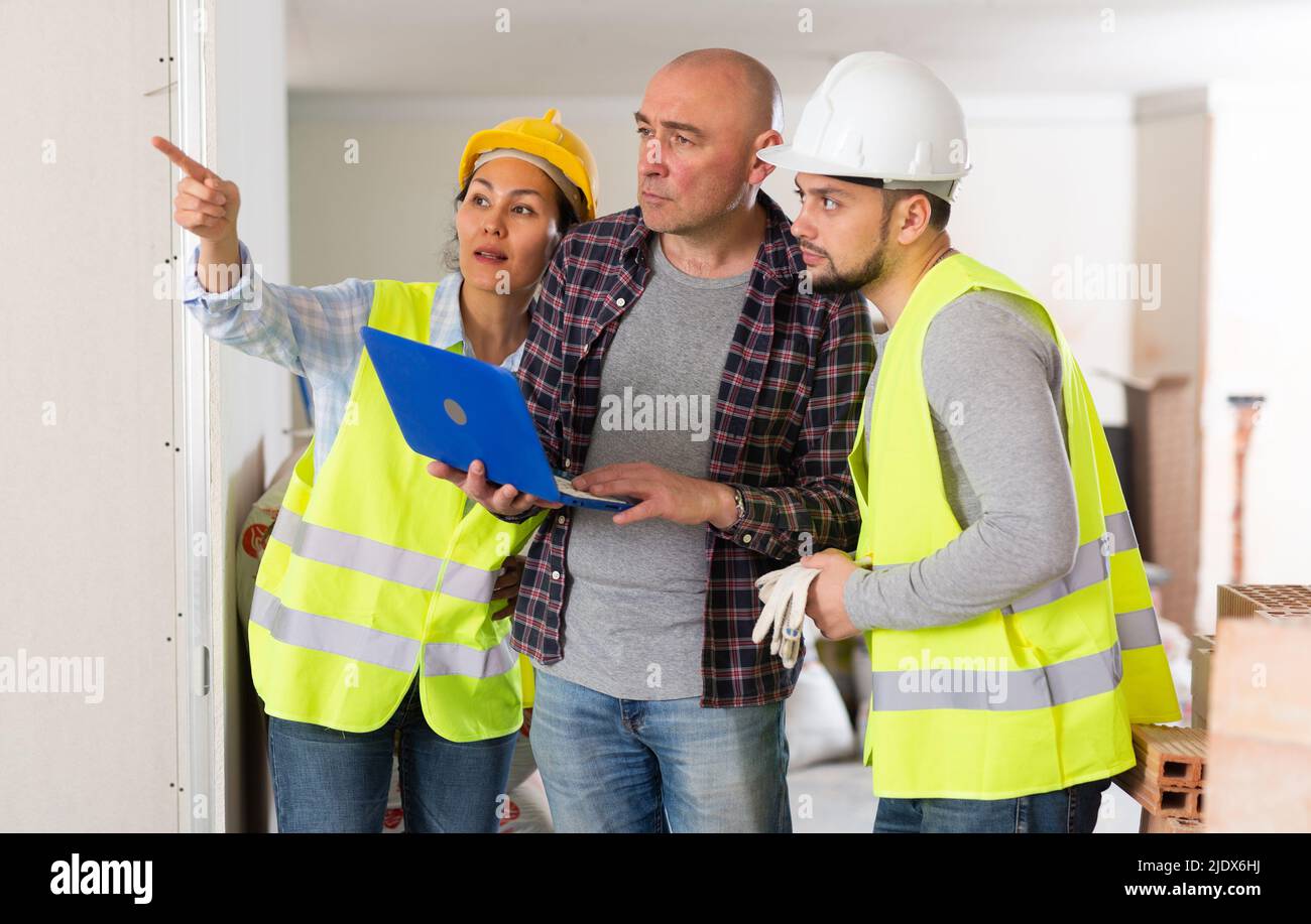Homeowner with laptop discussing home renovation with builders Stock ...
