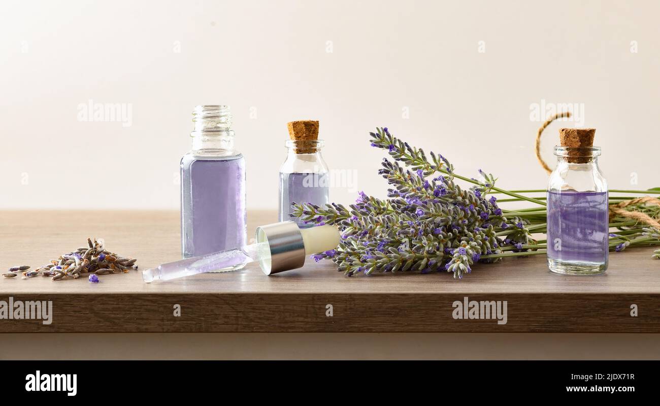 Medicinal lavender extract in glass bottles on wooden table with bunch ...