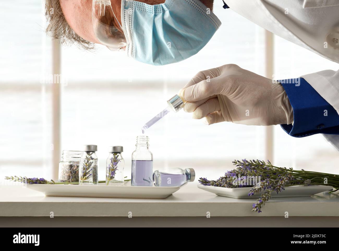 Scientist developing a product with lavender essence in glass vials on ...