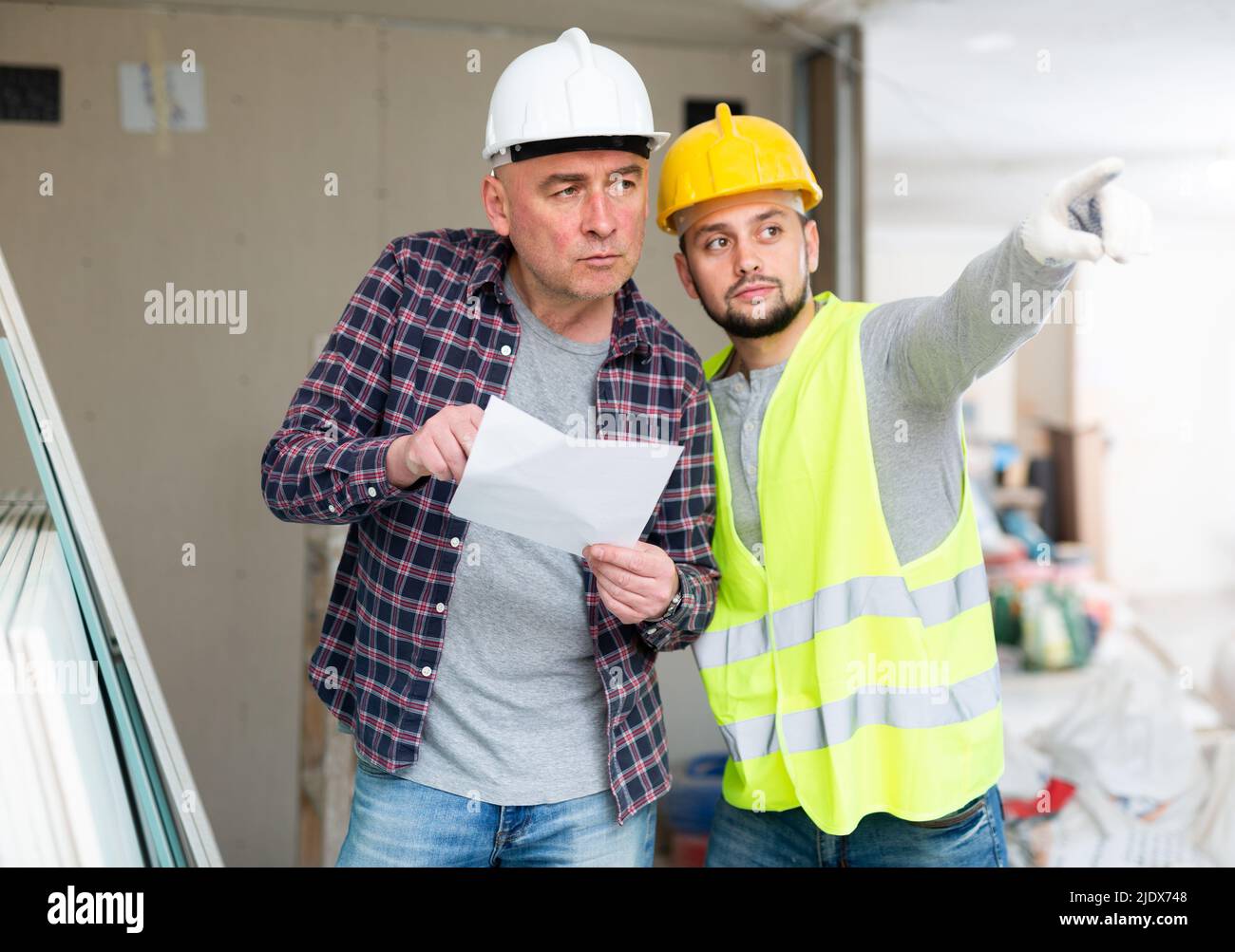 Architect and builder discussing documentation in construction site ...