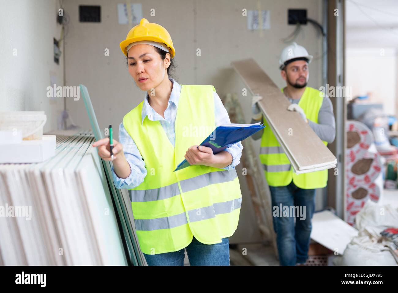 Female building inspector taking inventory of materials at construction ...