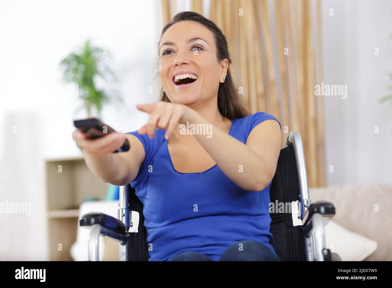 female in wheelchair elevision remote control pointing to tv Stock ...