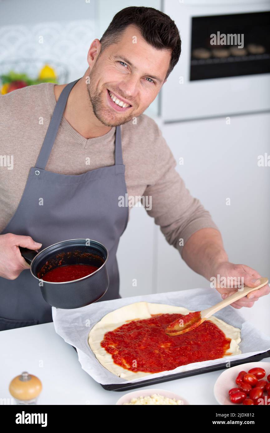 pouring tomato sauce on a pizza dough Stock Photo - Alamy