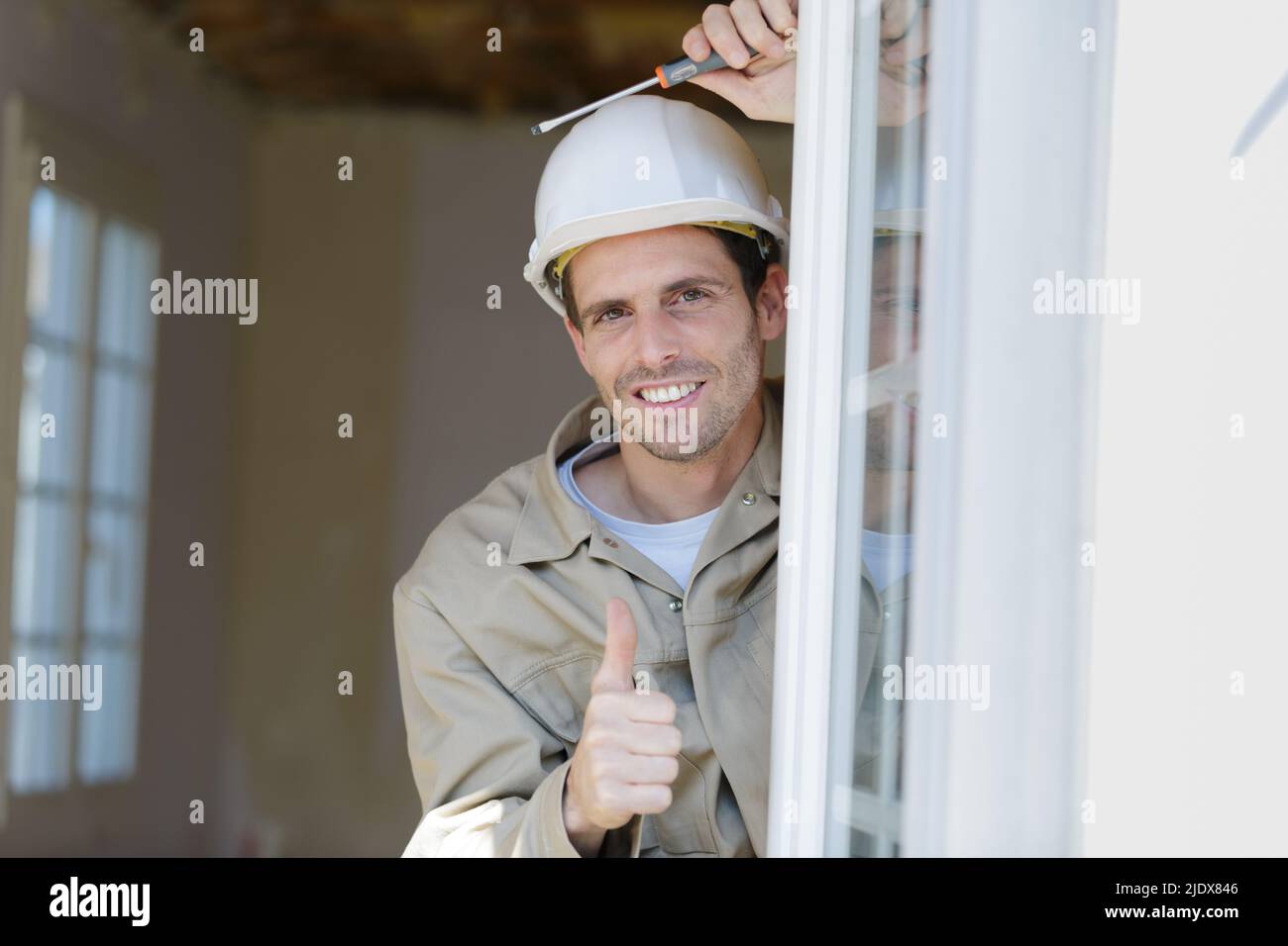 male builder making thumbs up gesture by open window Stock Photo - Alamy