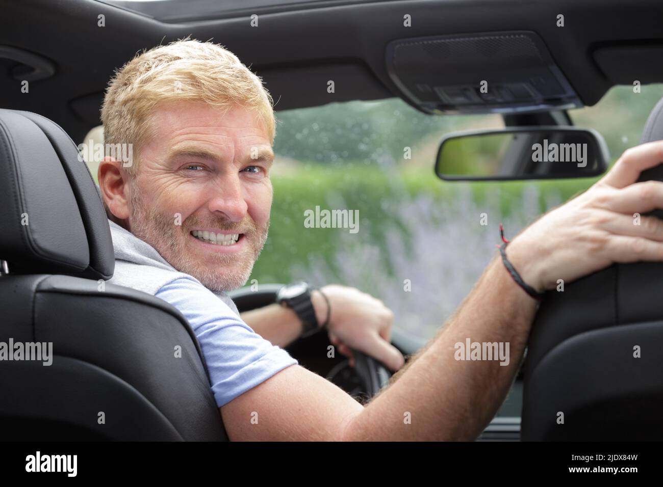 portrait of mature male driver turning to back of car Stock Photo - Alamy