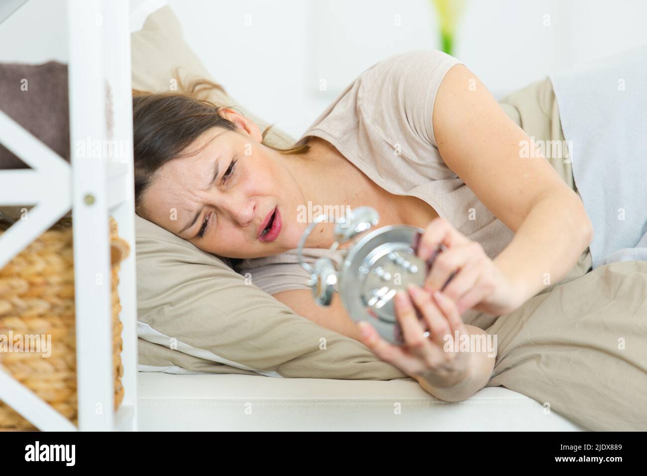 woman in bed looking at alarm clock with panic Stock Photo - Alamy