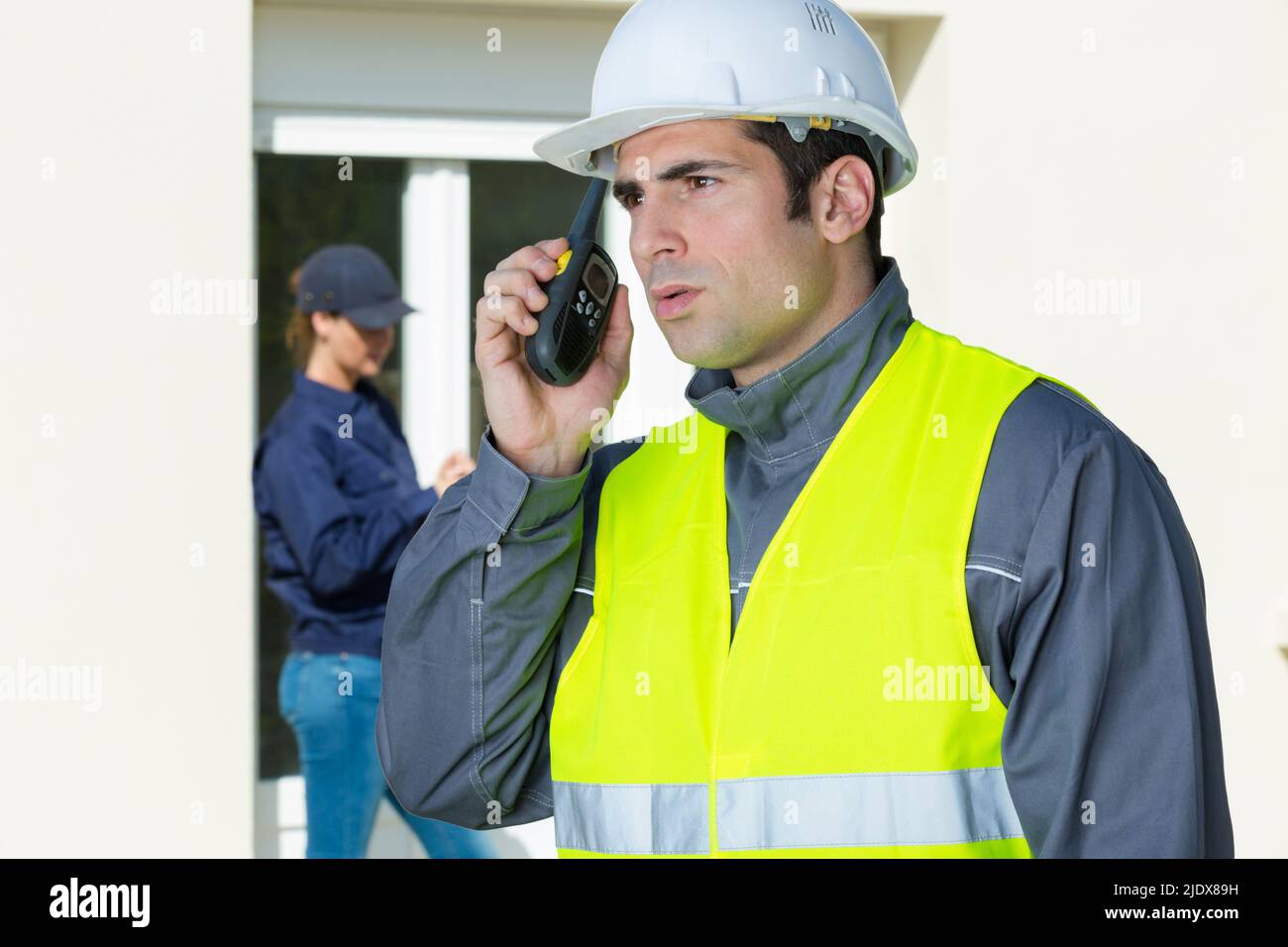 male worker using walkie-talkie with colleague in background Stock ...